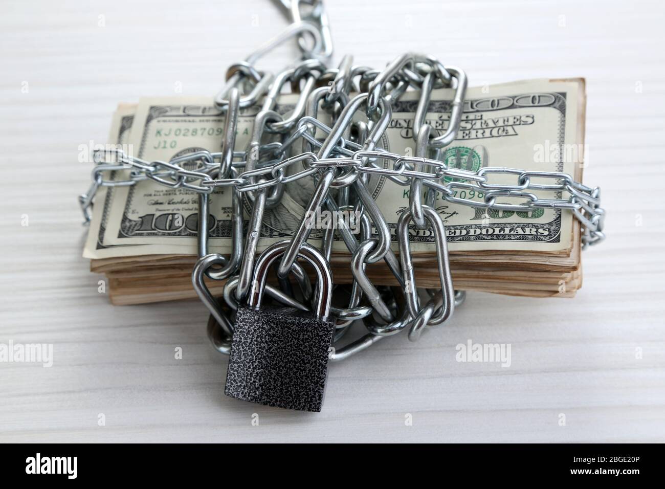 Dollars currency with lock and chain on wooden table Stock Photo - Alamy