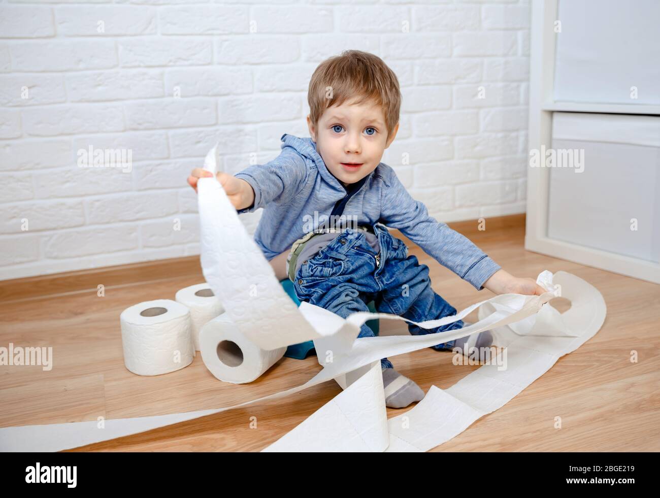 Lovely child sitting on potty and playing with toilet paper Stock Photo ...
