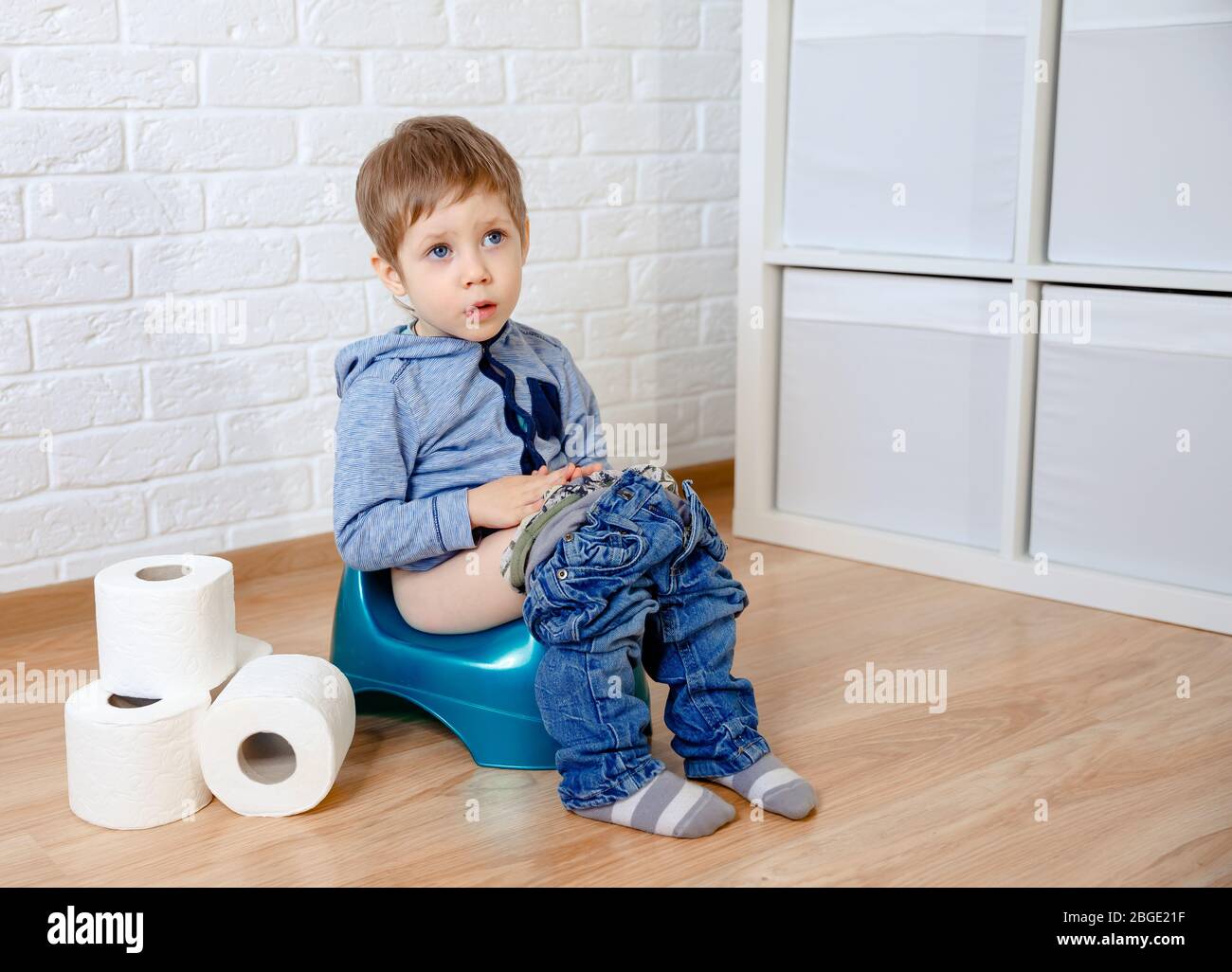 Child sitting on the potty with toilet paper. Colic, bloating, pain ...