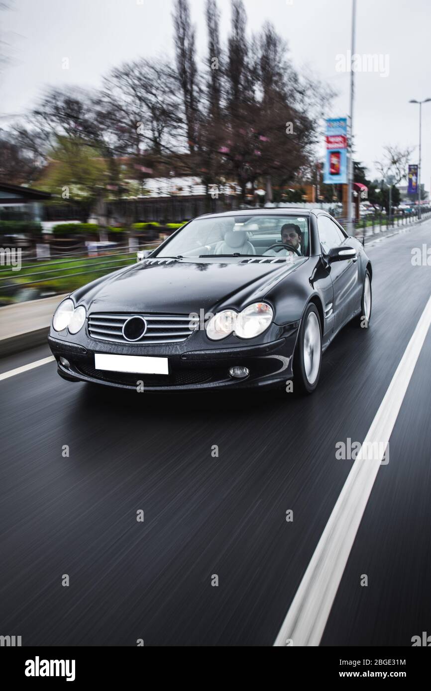 Business model sedan on city roads in rain, angle view Stock Photo - Alamy