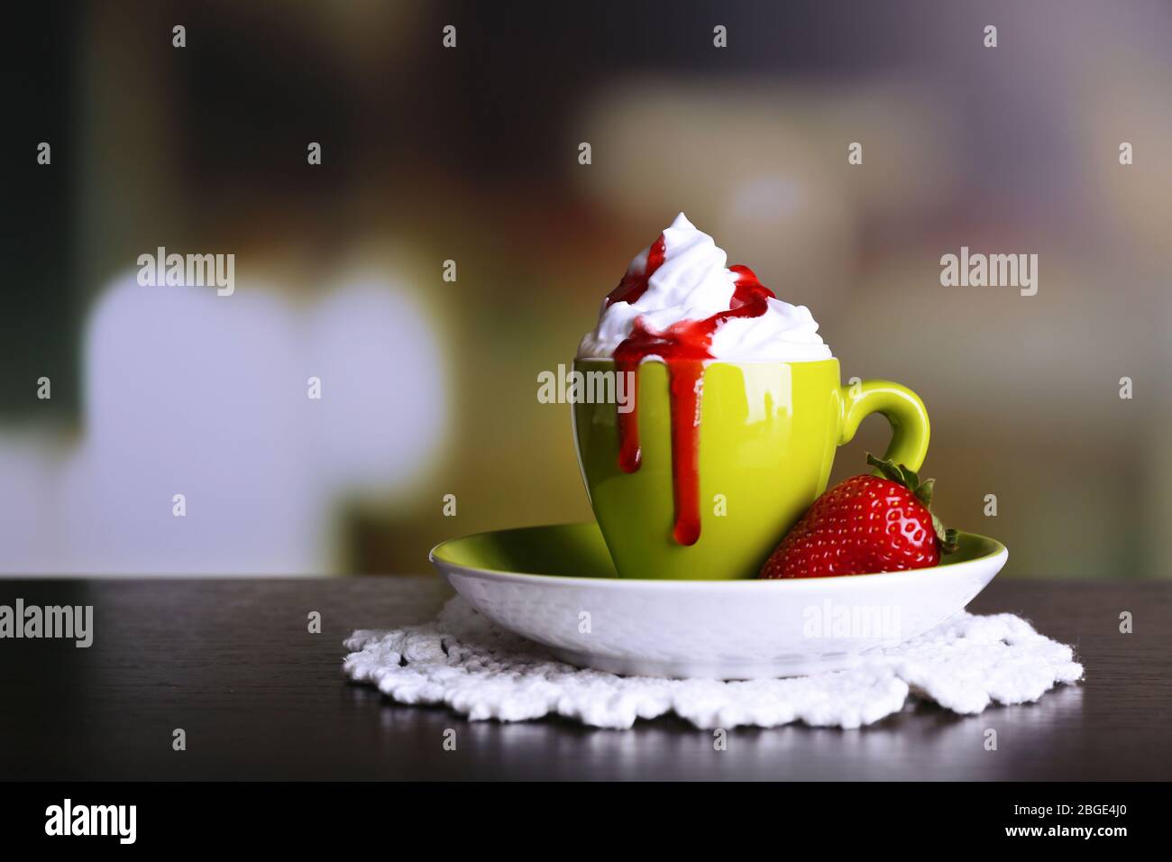Cup of coffee with cream and strawberry sauce on color wooden table, on ...