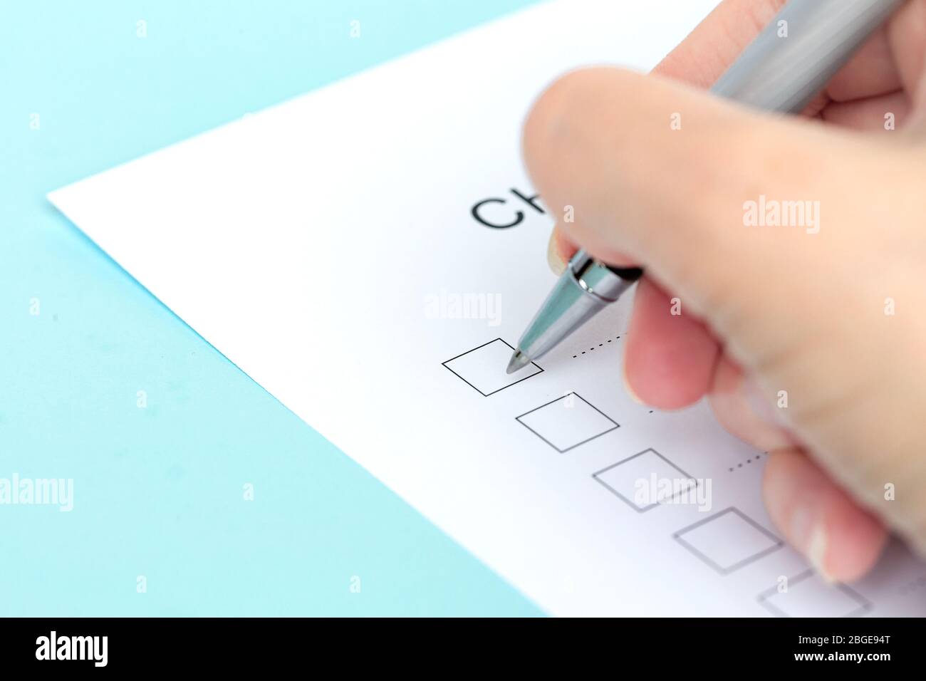 Close-up of a women hand marking on Checklist with pen on a blue ...