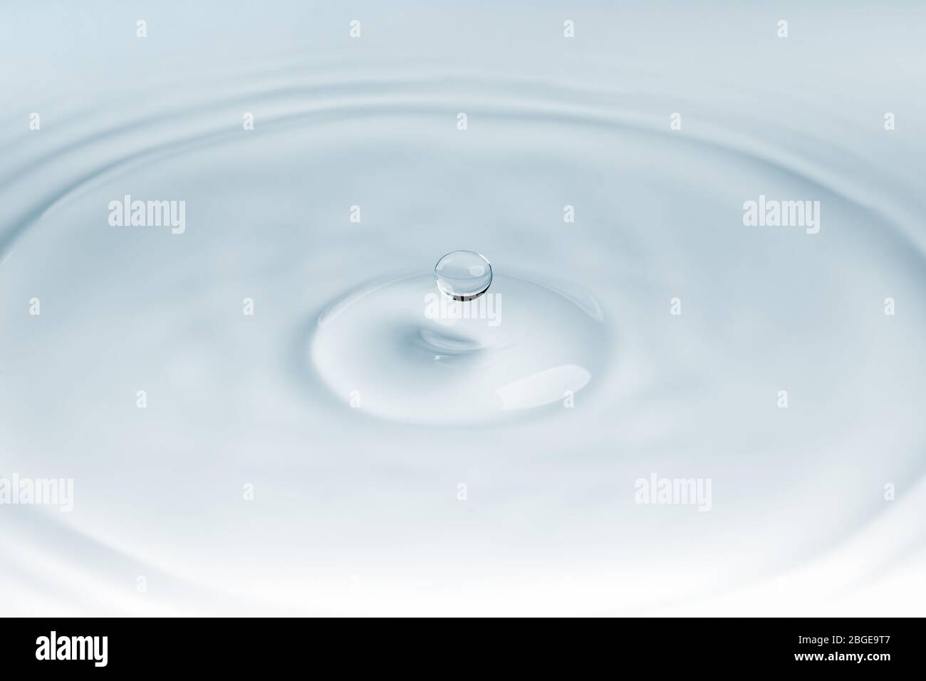 Small droplet of water falling over some ripple effect on the surface ...