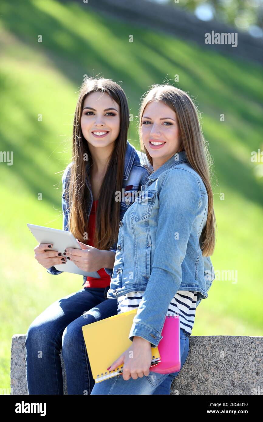 Happy students sitting in park Stock Photo - Alamy