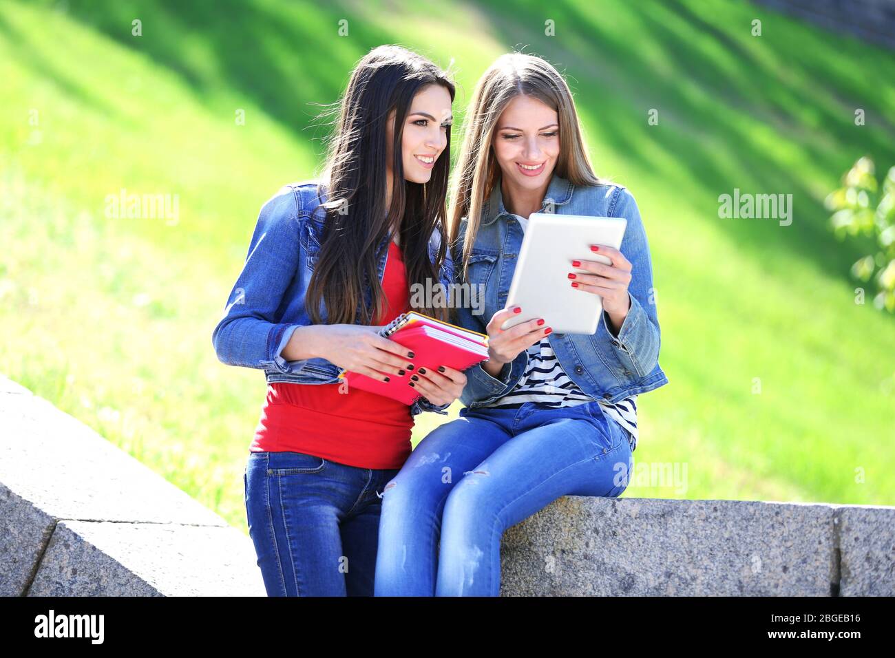Happy students sitting in park Stock Photo - Alamy