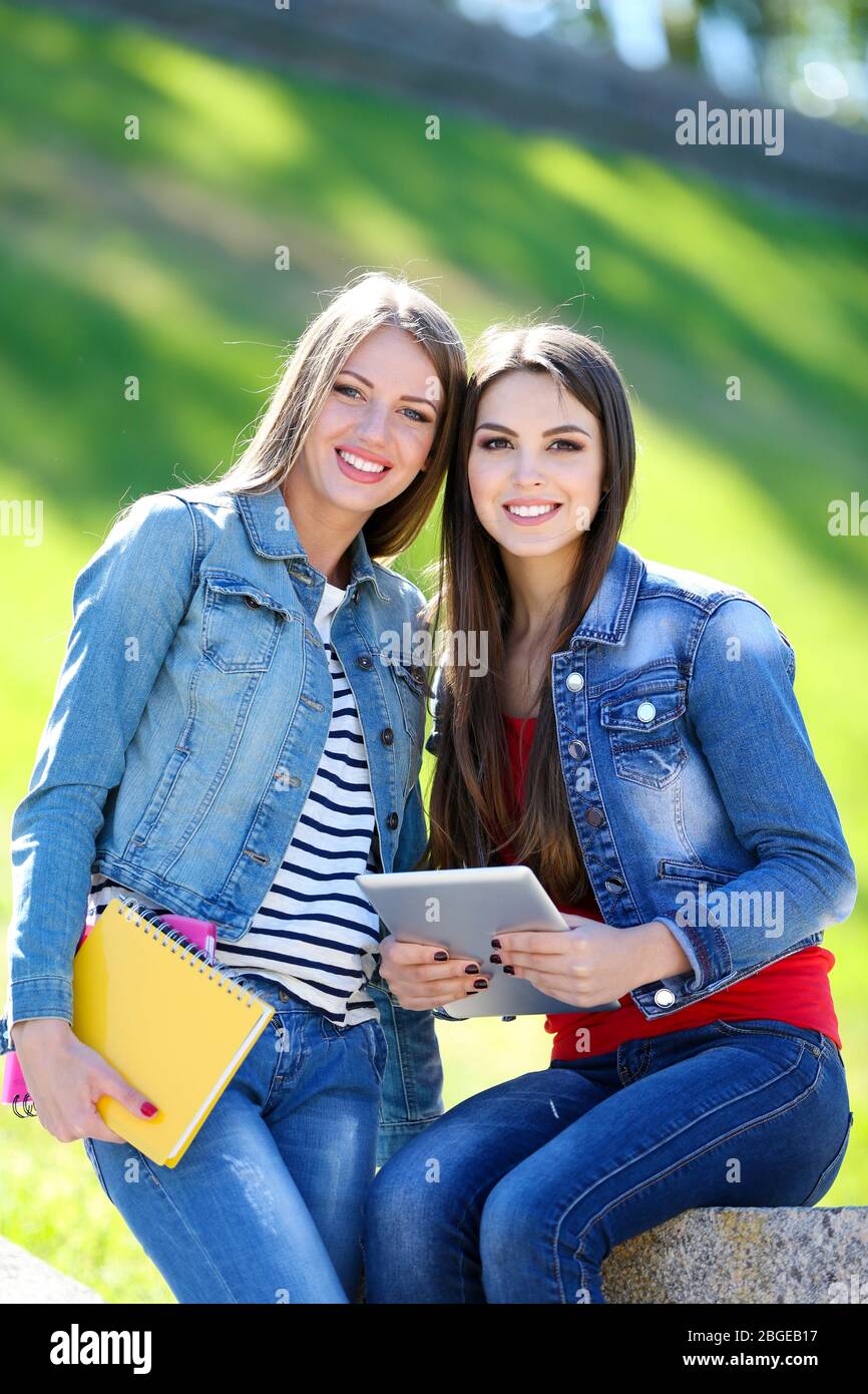Happy students sitting in park Stock Photo - Alamy