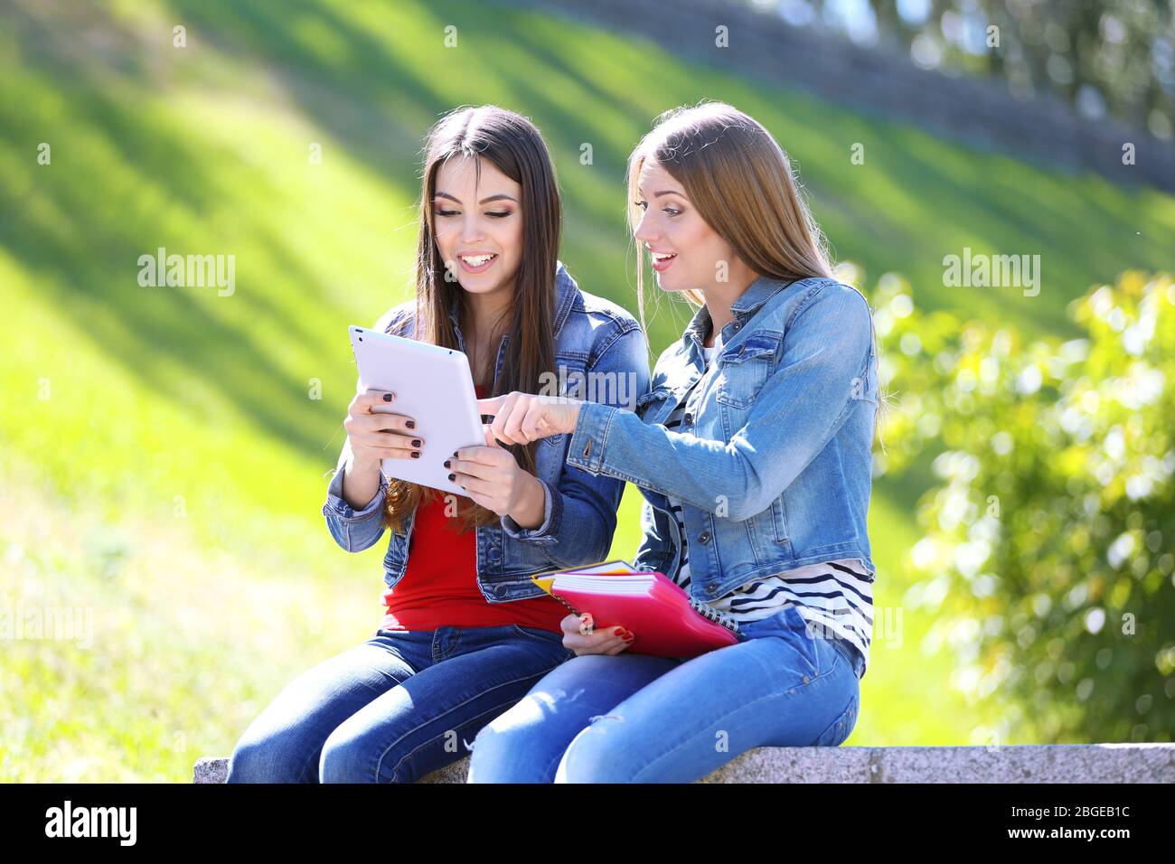 Happy students sitting in park Stock Photo - Alamy
