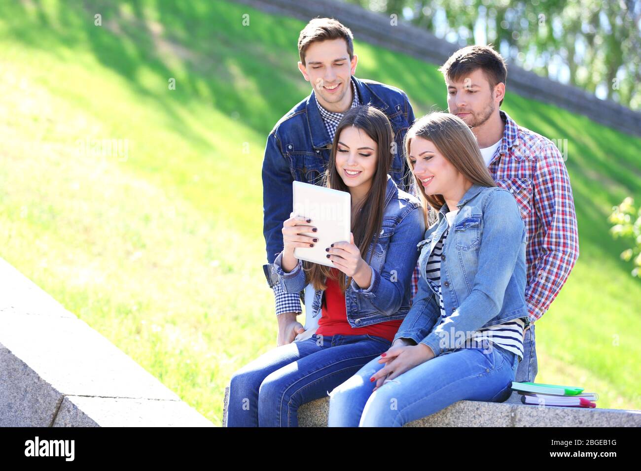Happy students sitting in park Stock Photo - Alamy