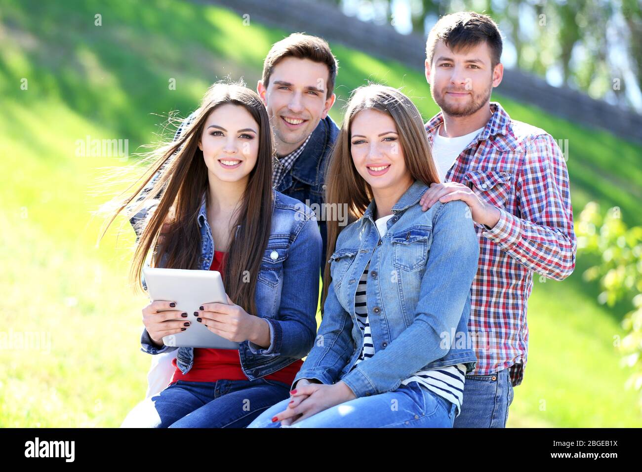 Happy students sitting in park Stock Photo - Alamy