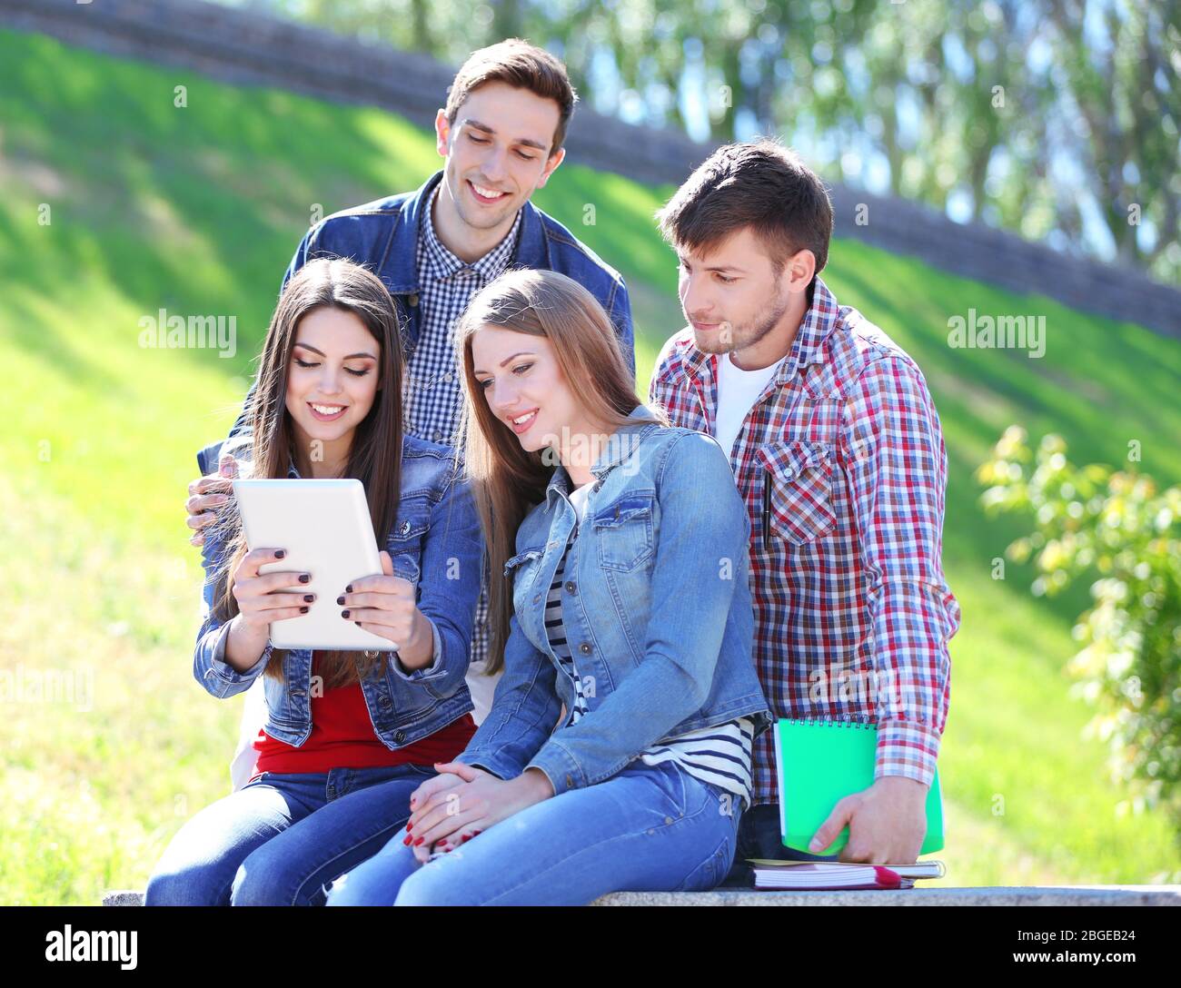 Happy students sitting in park Stock Photo - Alamy