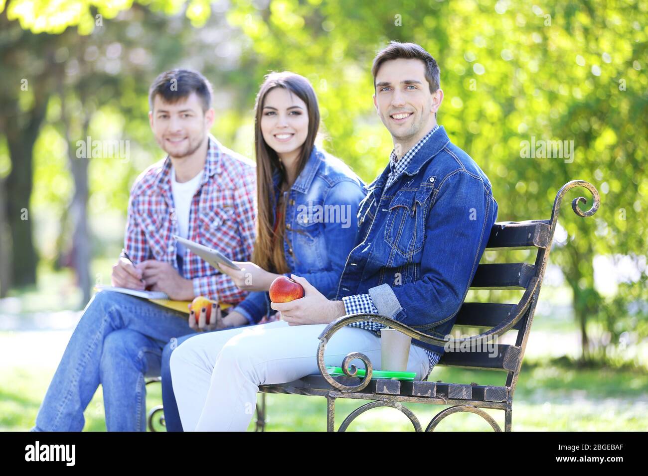 Happy students sitting in park Stock Photo - Alamy