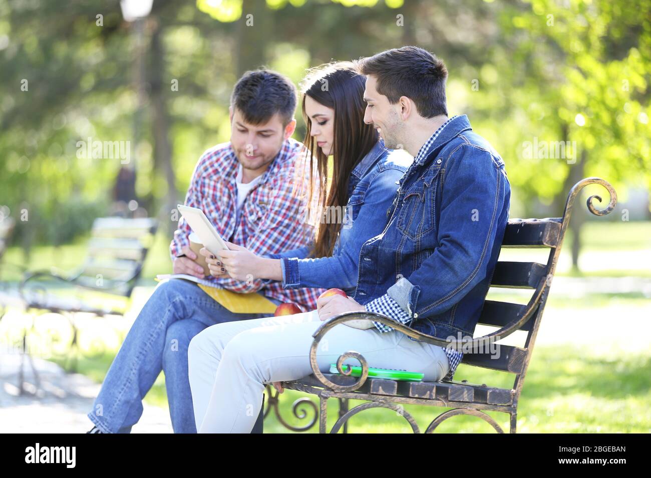 Happy students sitting in park Stock Photo - Alamy
