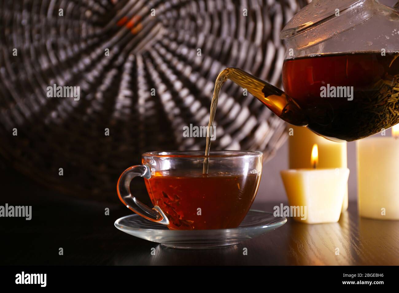 Tea pouring into glass cup on dark background Stock Photo - Alamy