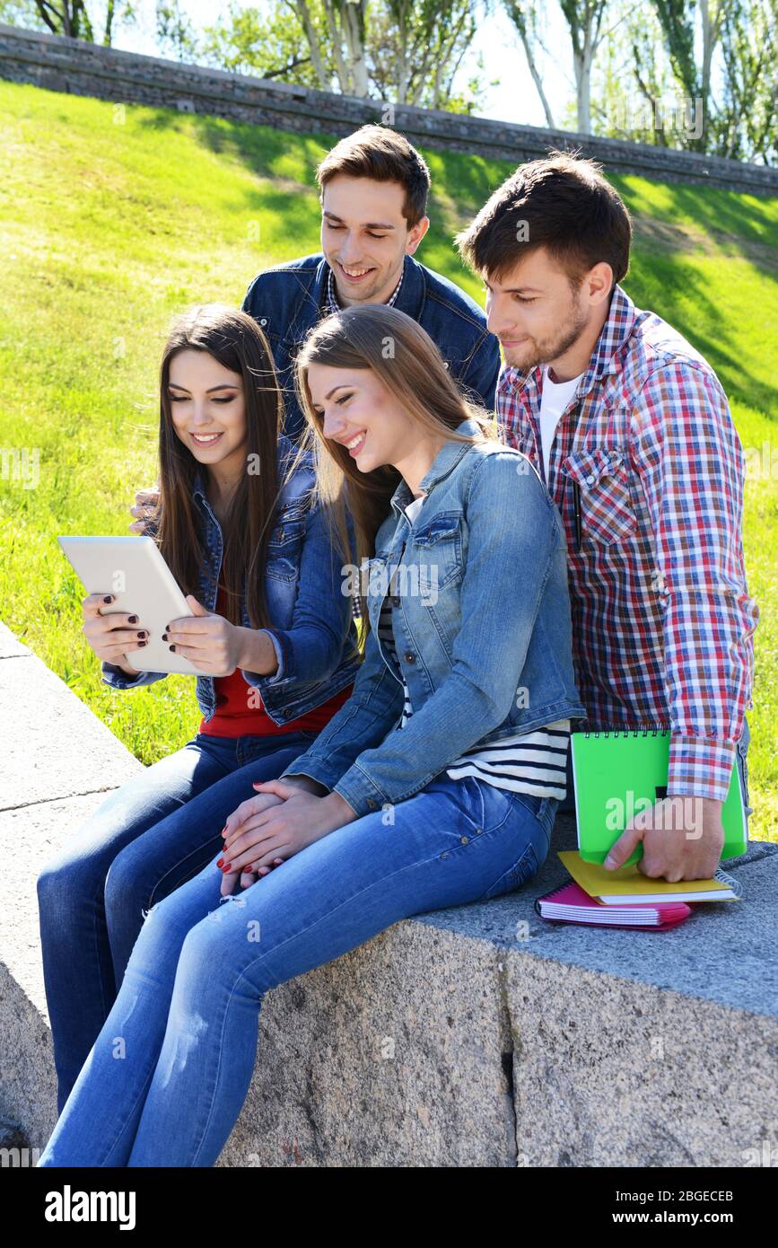 Happy students sitting in park Stock Photo - Alamy