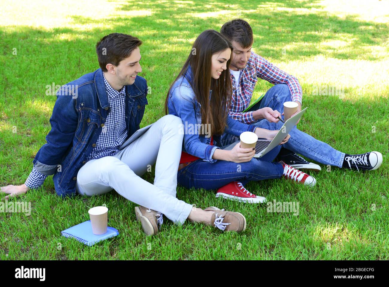 Happy students sitting in park Stock Photo - Alamy