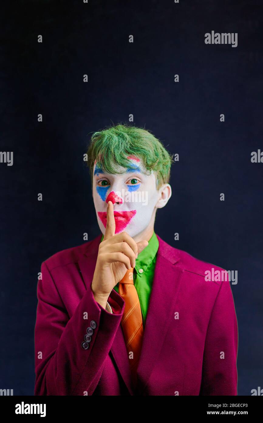 Man in mime makeup cosplay with green hair and a red suit an orange tie ...