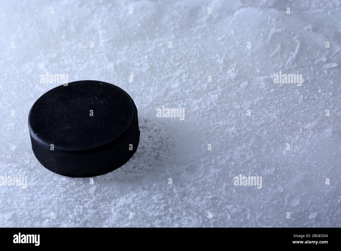 Black hockey puck on ice rink background Stock Photo - Alamy