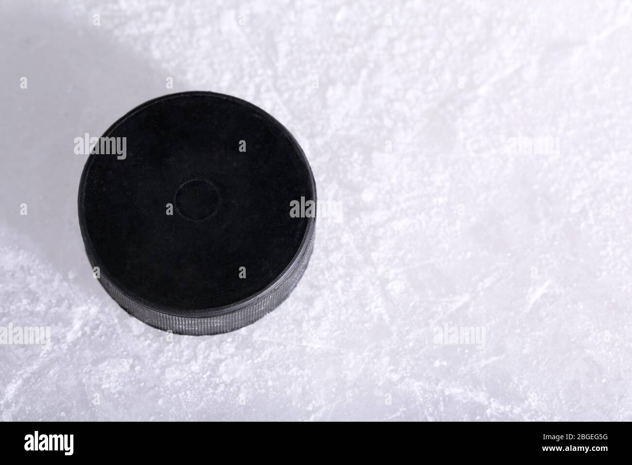 Black hockey puck on ice rink background Stock Photo - Alamy