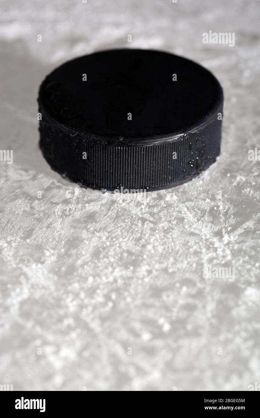 Black hockey puck on ice rink background Stock Photo - Alamy
