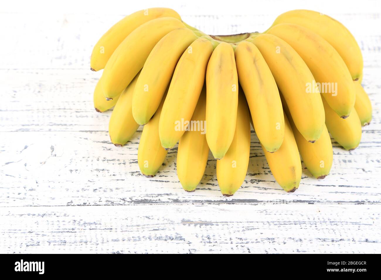 Bunch of mini bananas on color wooden background Stock Photo - Alamy