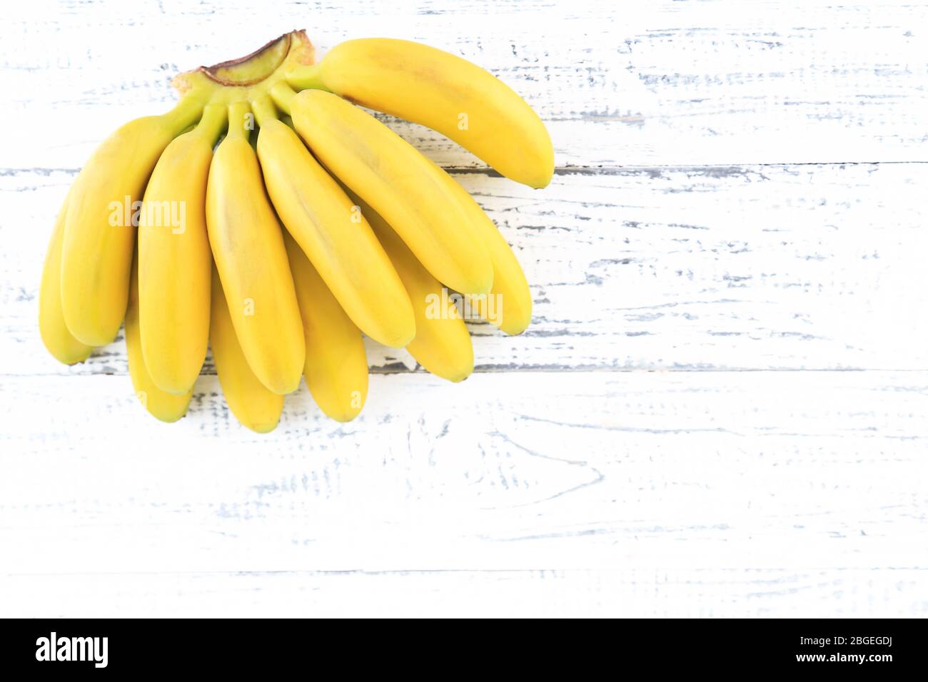 Bunch of mini bananas on color wooden background Stock Photo - Alamy