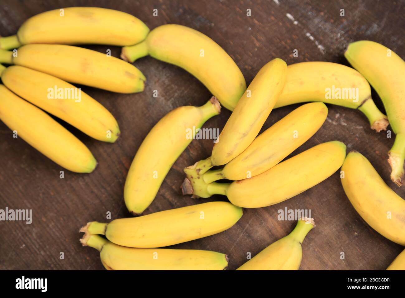 Bunch of mini bananas on color wooden background Stock Photo - Alamy