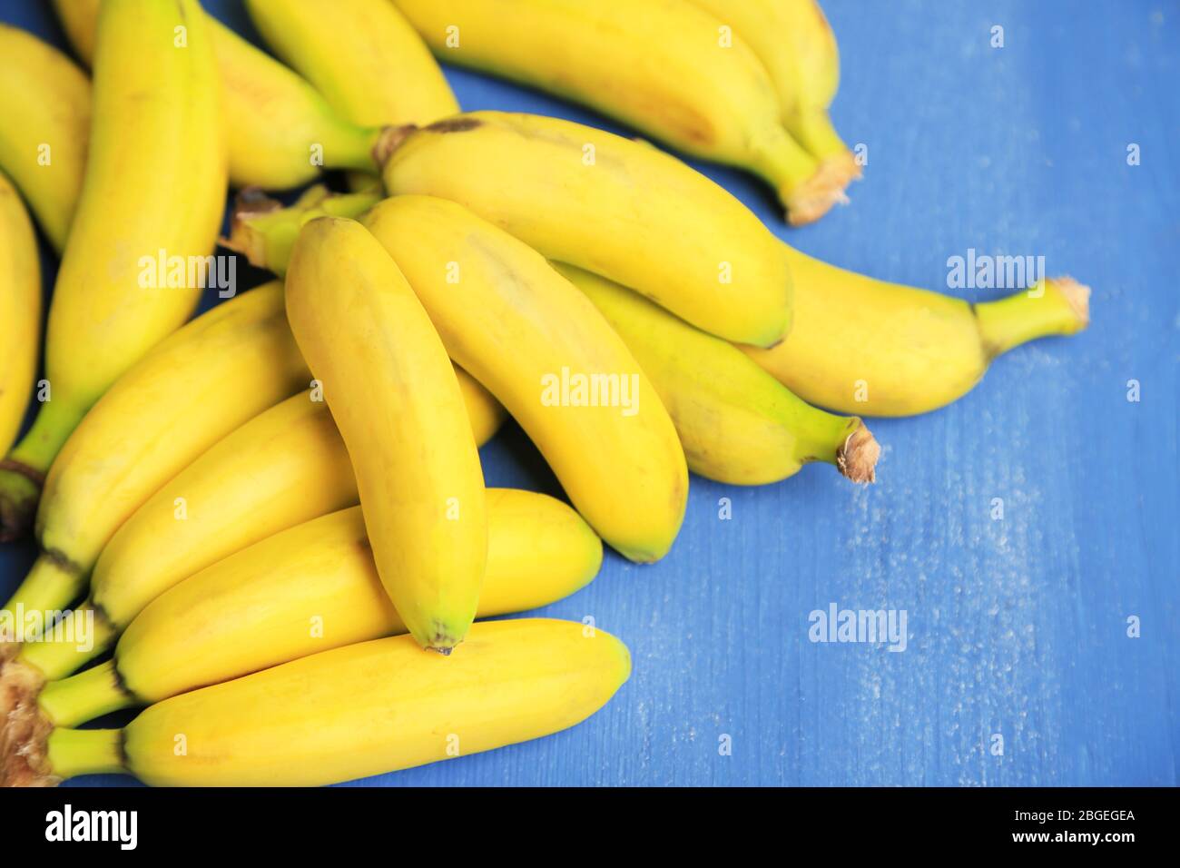 Bunch of mini bananas on color wooden background Stock Photo - Alamy