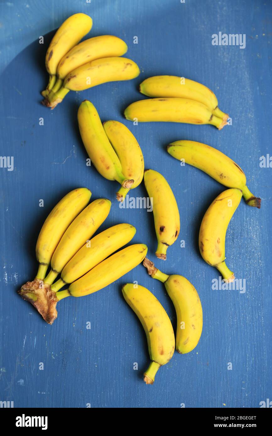 Bunch of mini bananas on color wooden background Stock Photo - Alamy