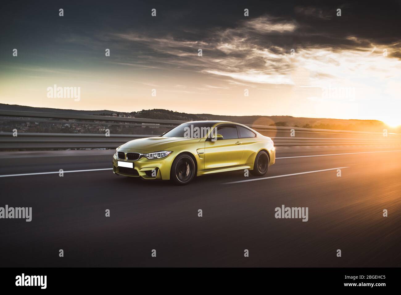 Yellow luxury sedan with black tuning on the highway in the dusk time ...