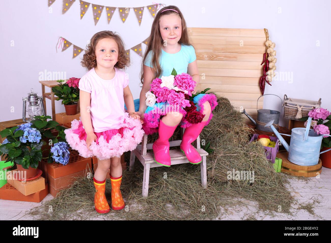 Beautiful small girls in petty skirts holding flowers on country style ...