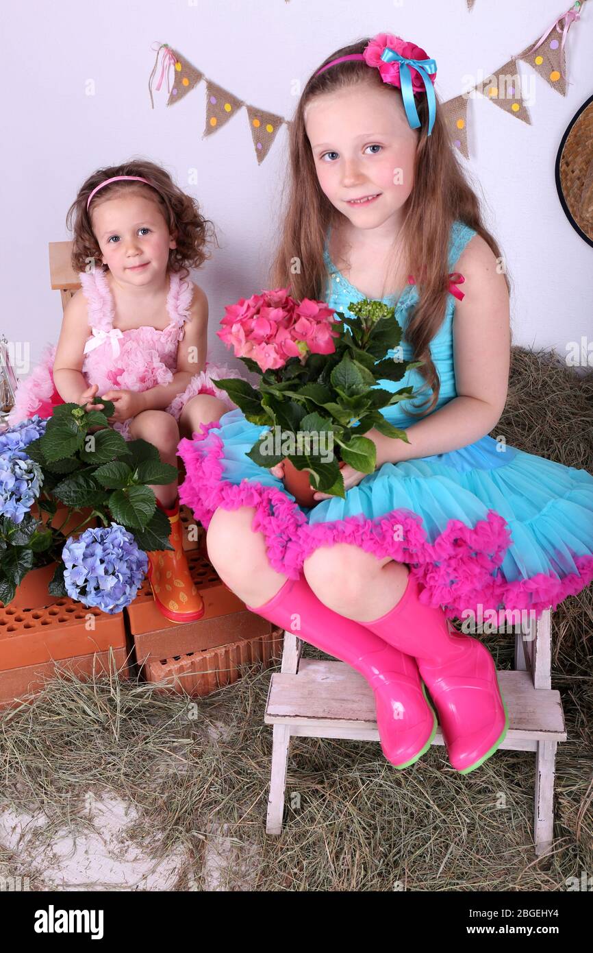 Beautiful small girls in petty skirts holding flowers on country style ...