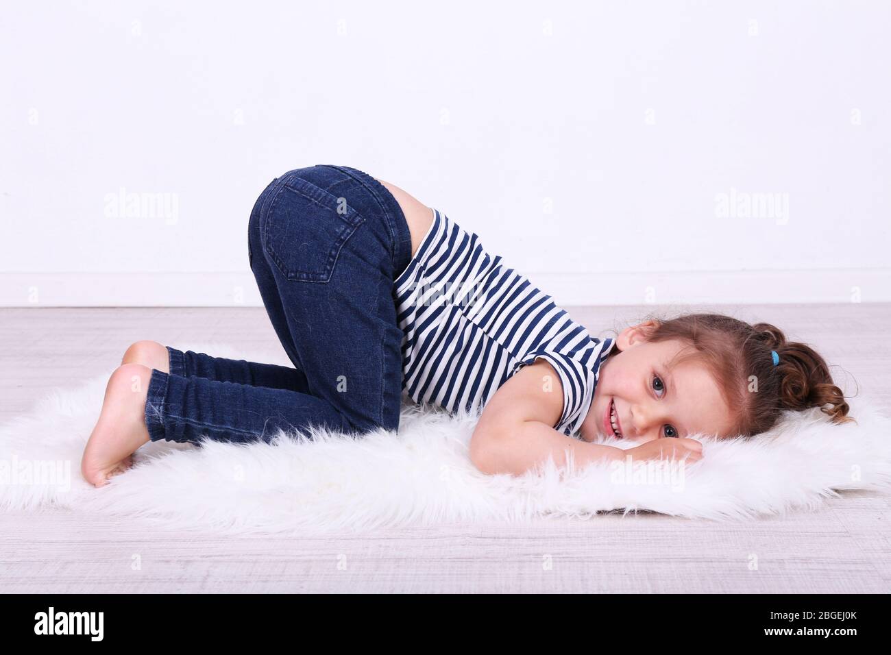 Beautiful small girl lying on floor on wall background Stock Photo - Alamy