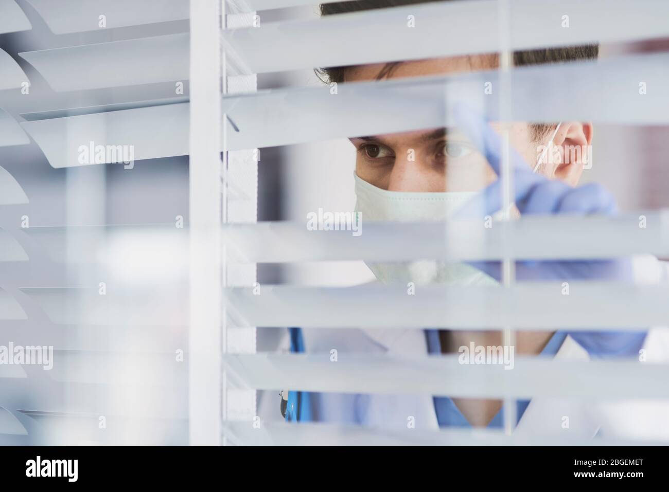 Doctor peeking through the window into isolation ward Stock Photo - Alamy
