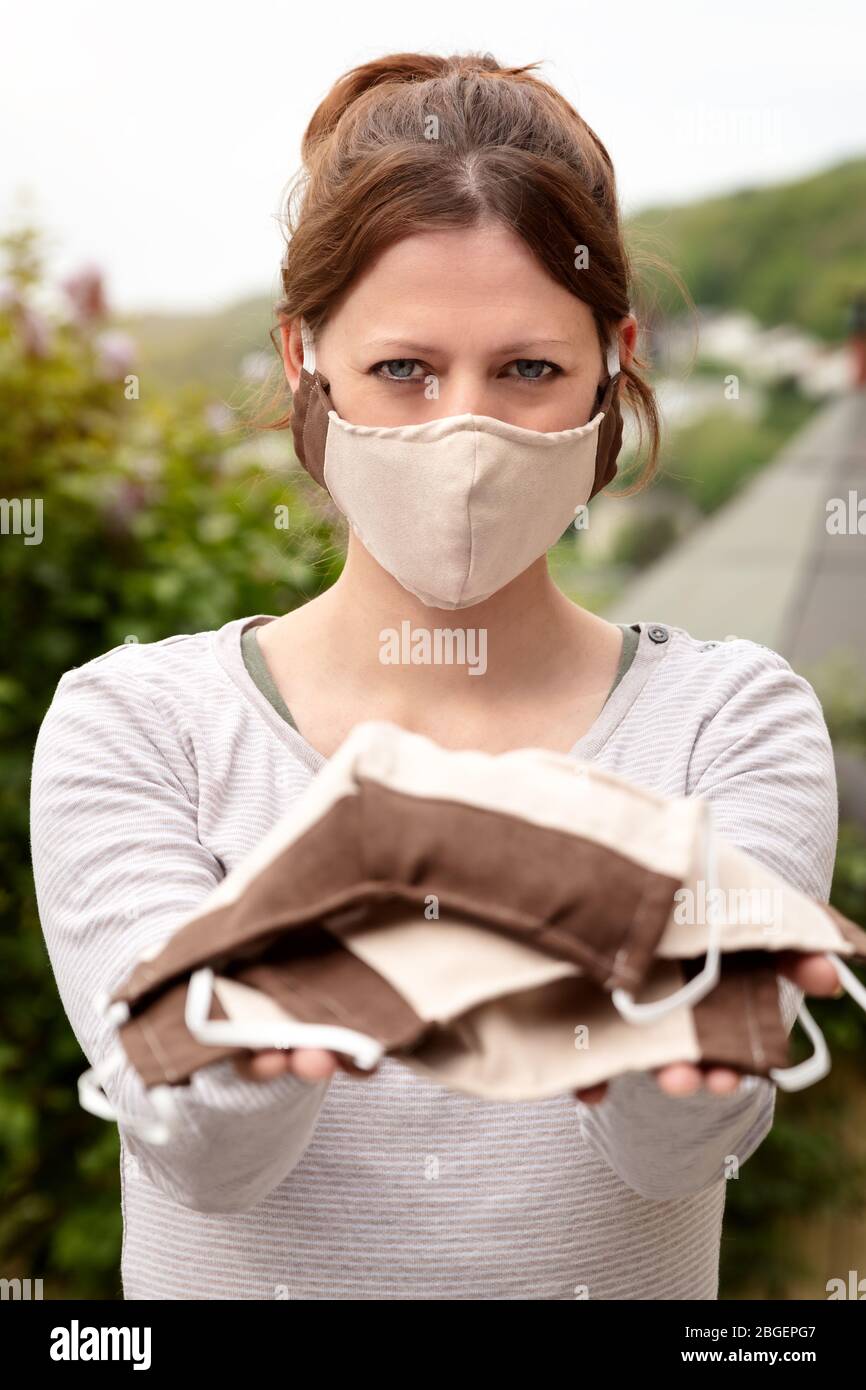 Woman is wearing and holding a homemade fabric cloth face mask ...