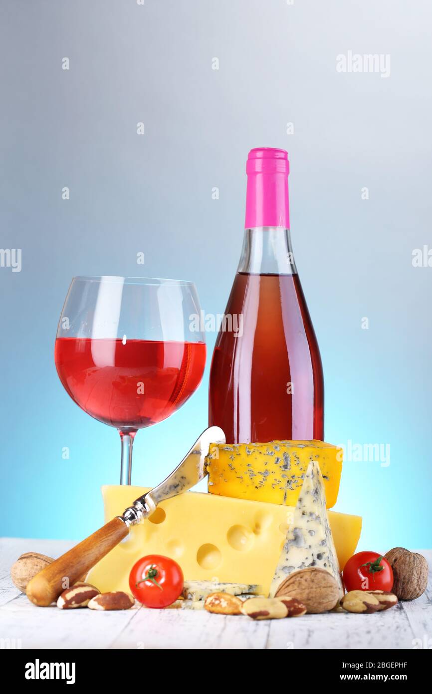 Pink wine and different kinds of cheese on colorful background Stock ...