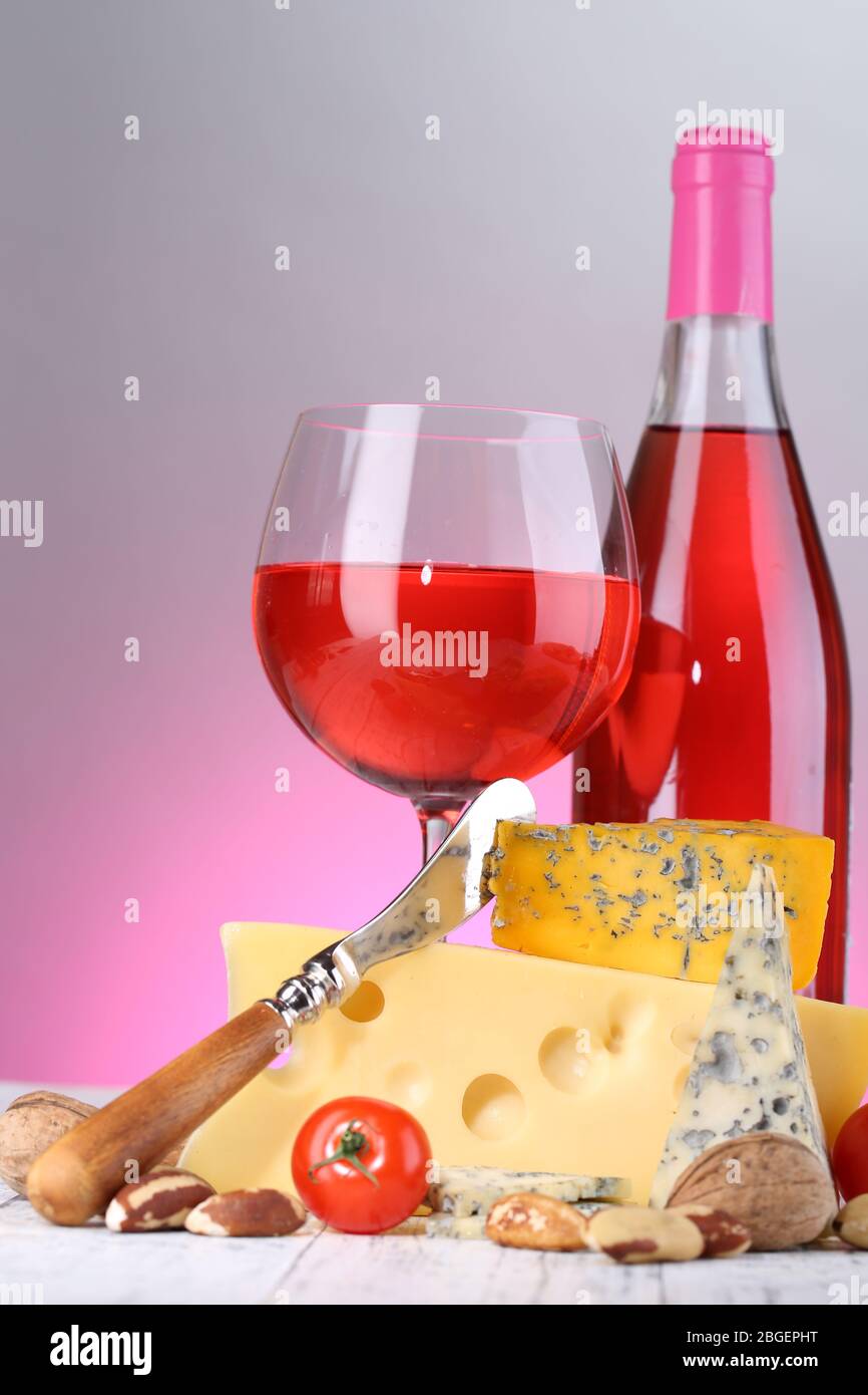 Pink wine and different kinds of cheese on colorful background Stock ...