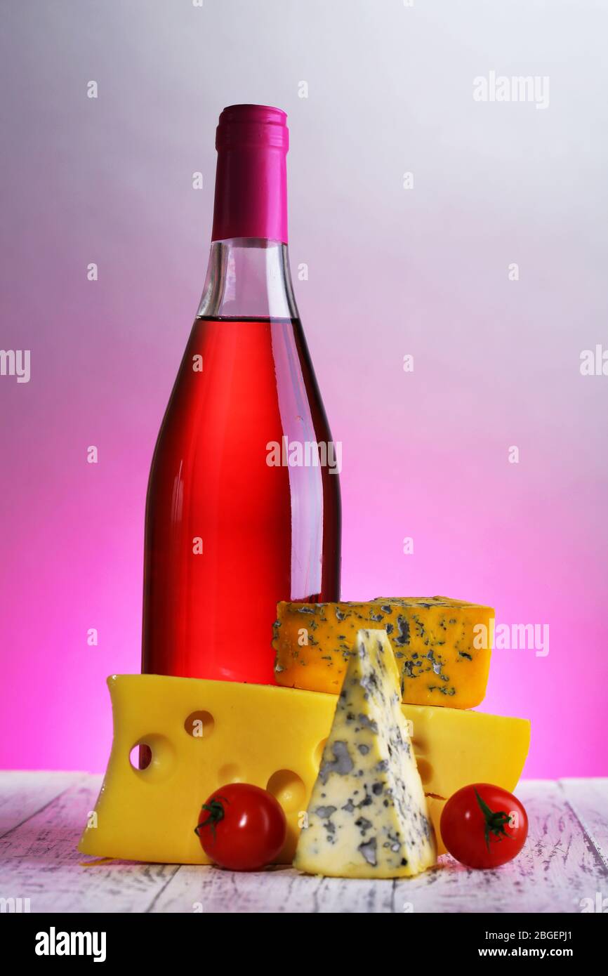 Pink wine and different kinds of cheese on colorful background Stock ...