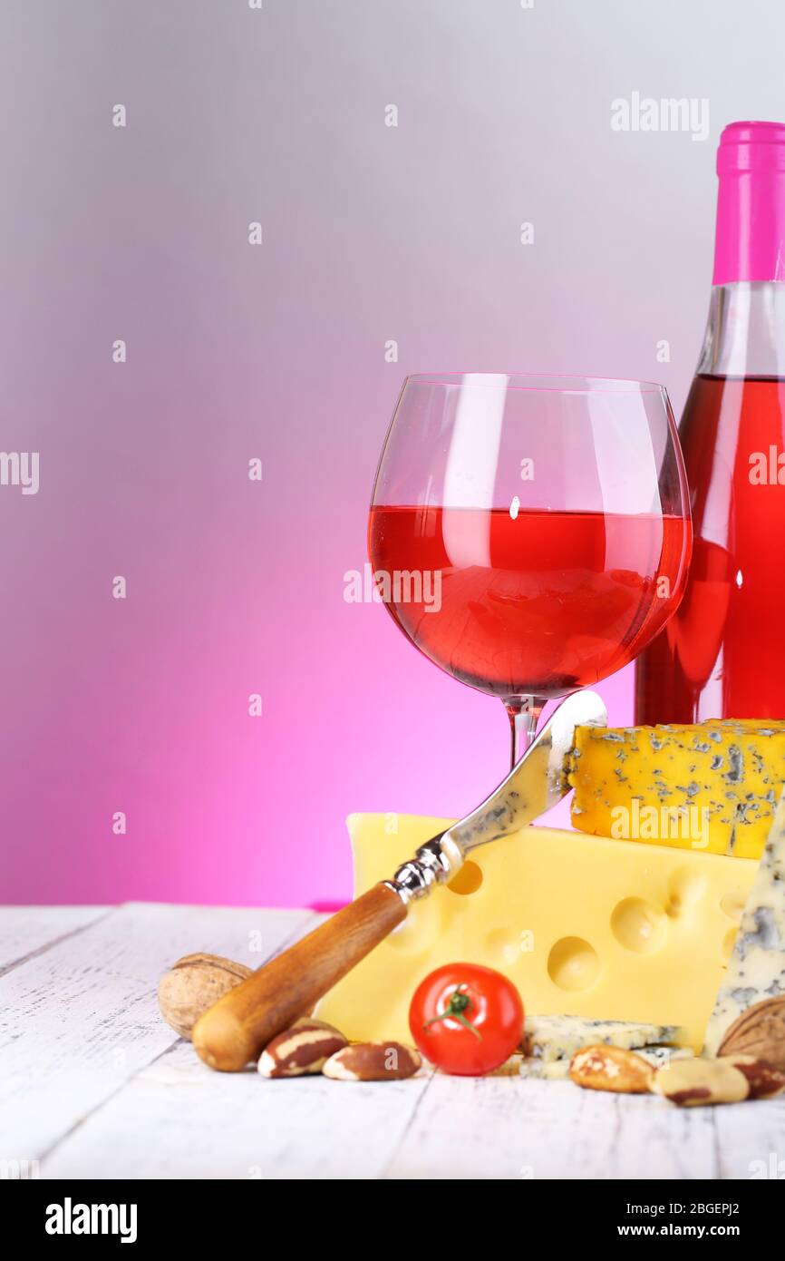 Pink wine and different kinds of cheese on colorful background Stock ...