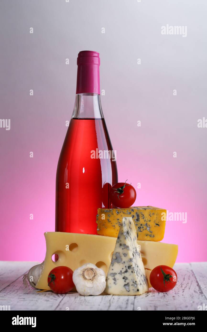 Pink wine and different kinds of cheese on colorful background Stock ...