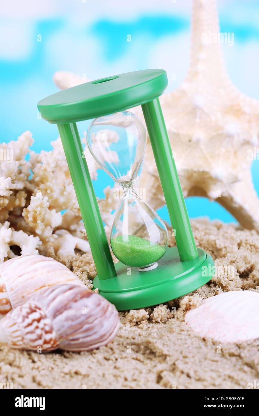 Hourglass in sand on bright background Stock Photo - Alamy