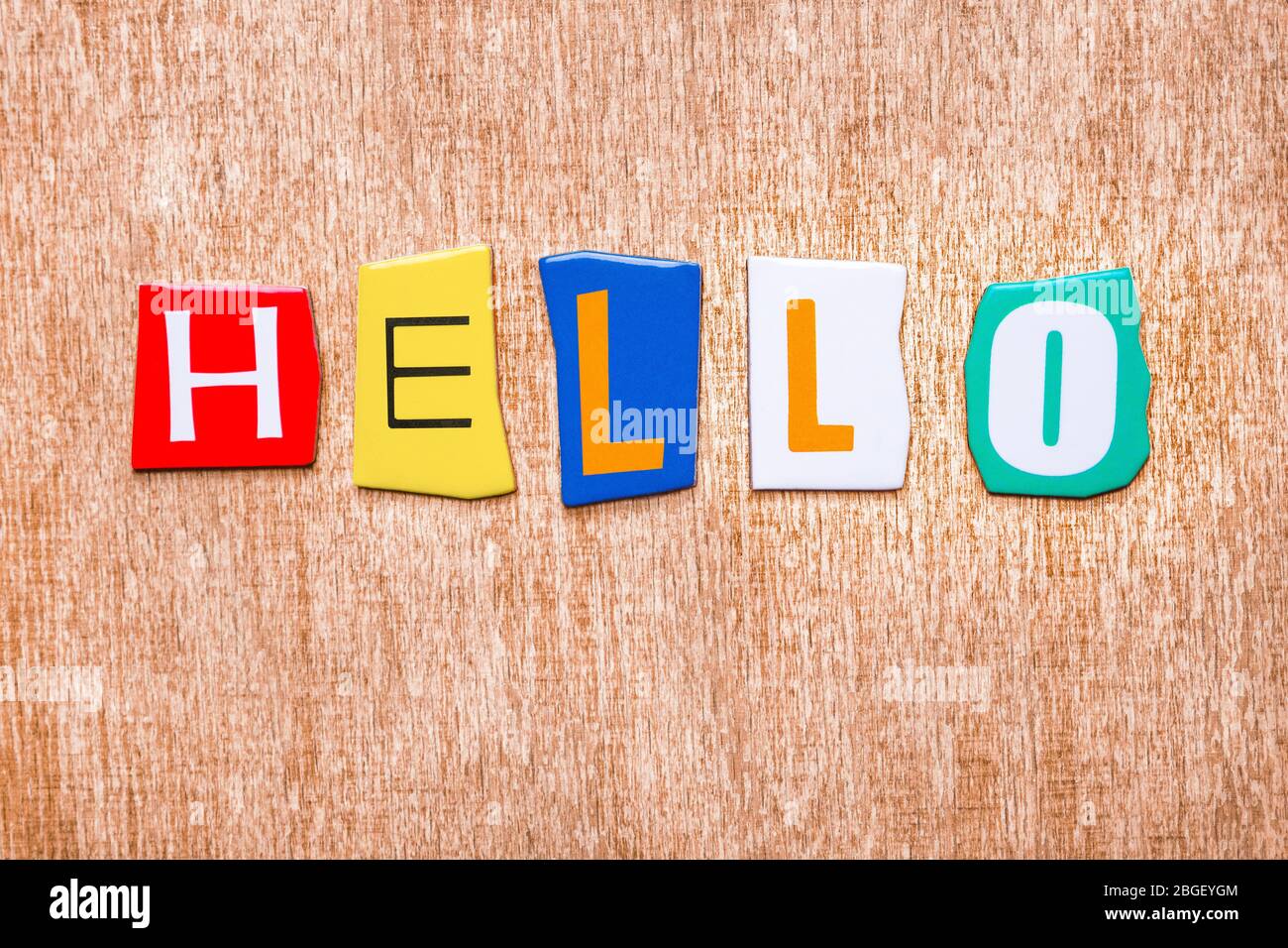 Multicolored letters scattered on wooden background and words hello ...