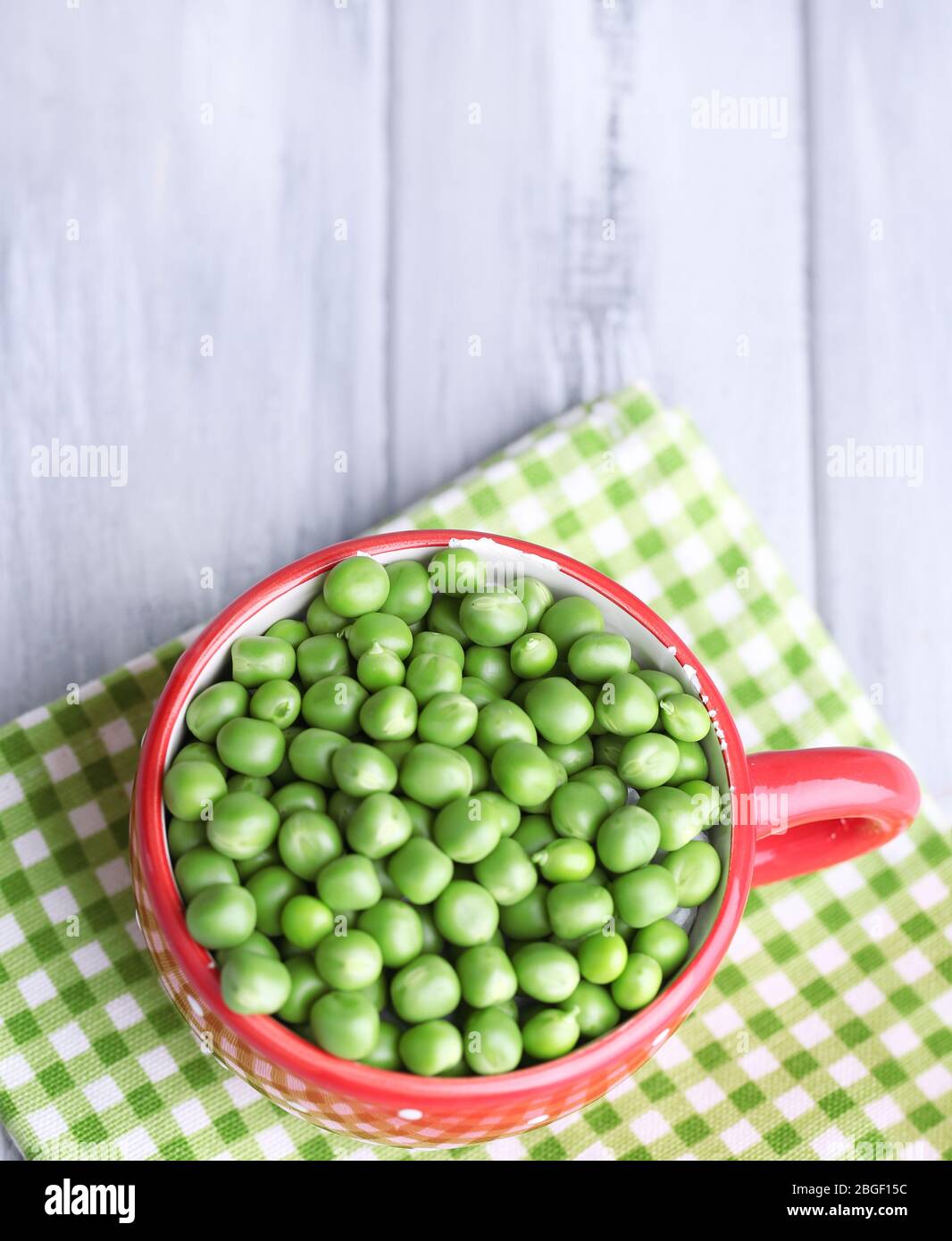 Green peas in red cup on wooden background Stock Photo - Alamy