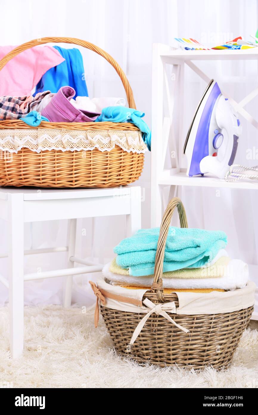 Colorful towels and clothes in baskets on table, on interior background ...