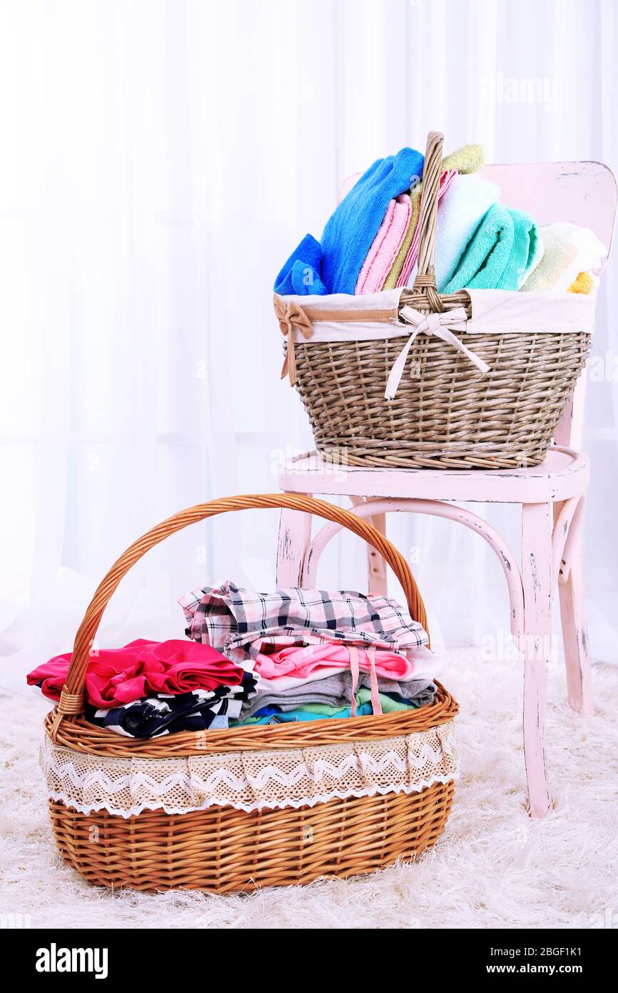 Colorful towels and clothes in baskets on table, on interior background ...