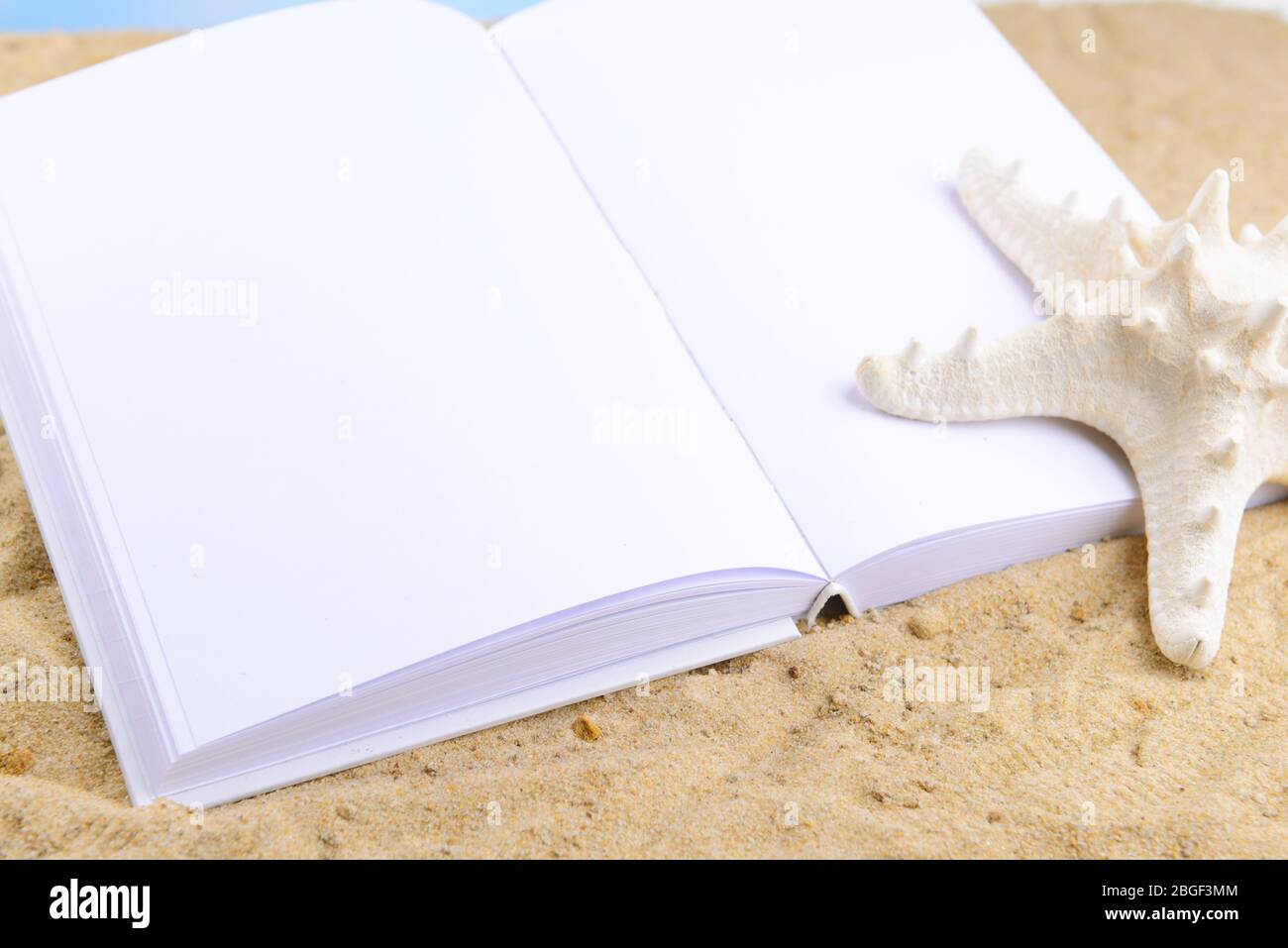 Open white book on sand background Stock Photo - Alamy