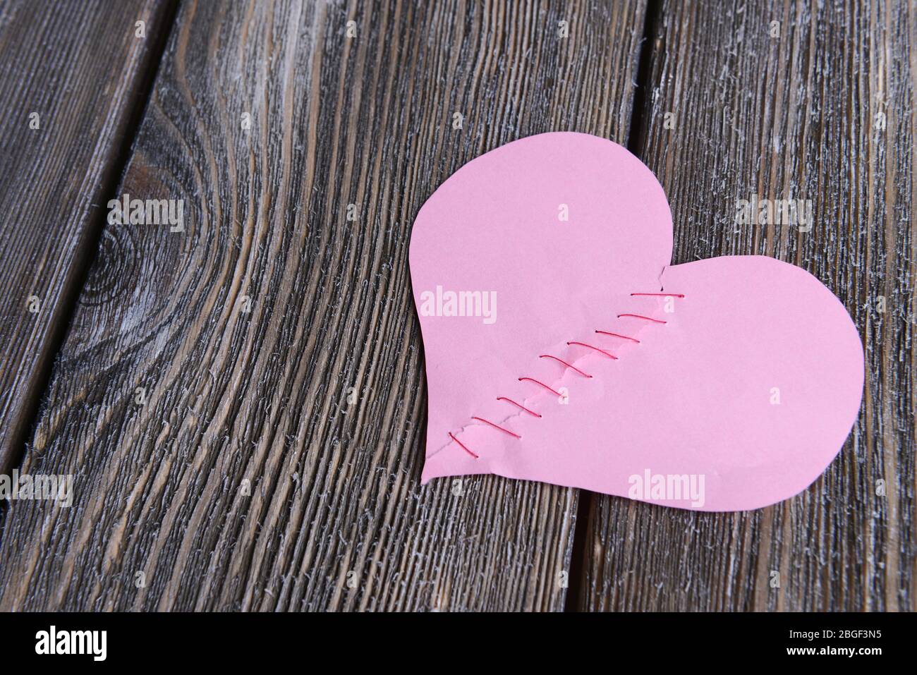 Broken heart and thread on wooden background Stock Photo - Alamy