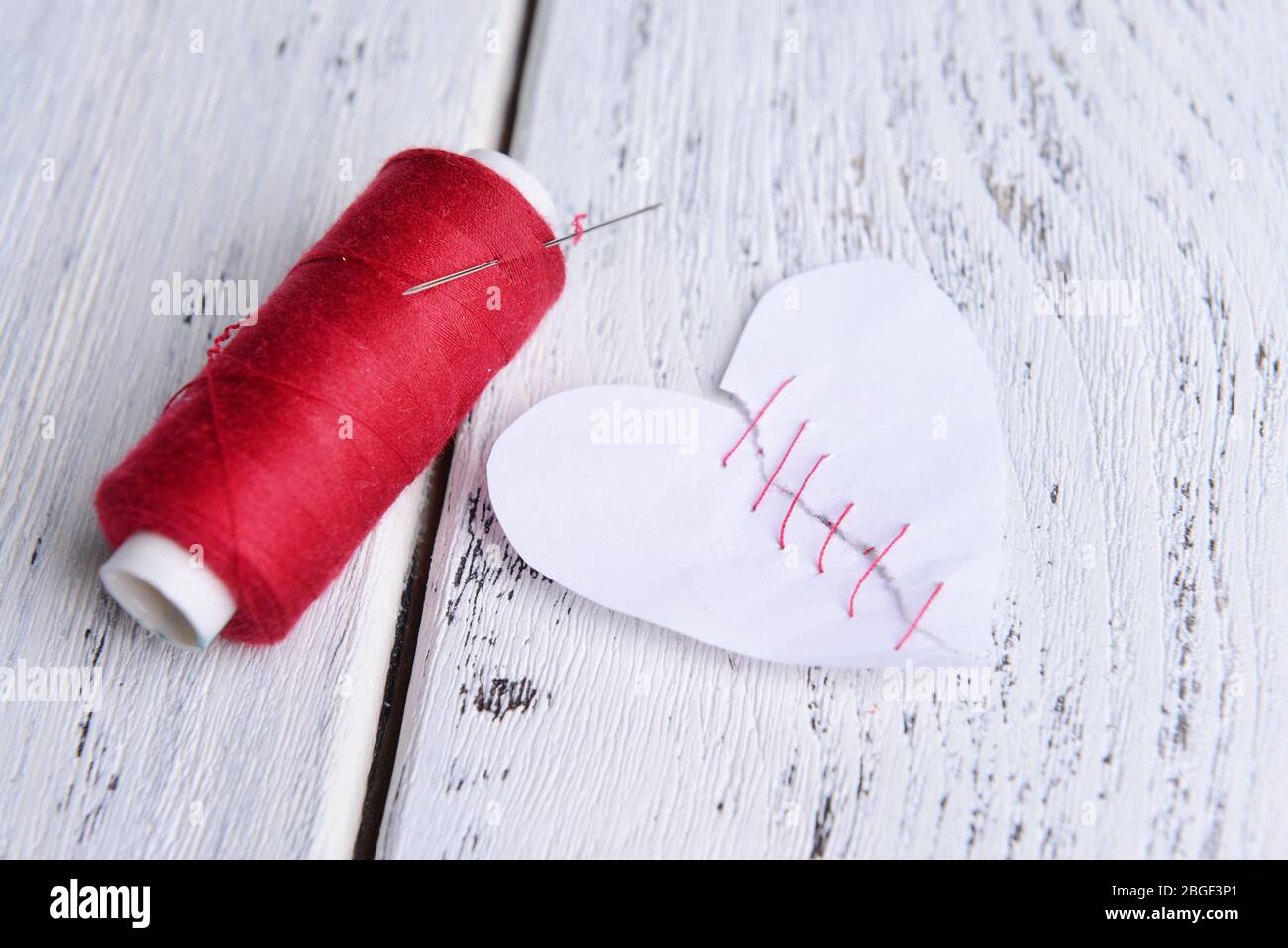 Broken heart and thread on wooden background Stock Photo - Alamy