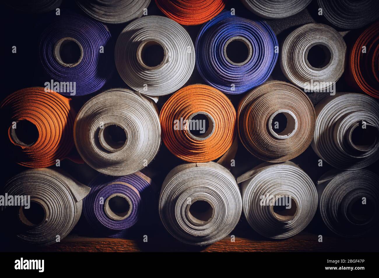 many textile rolls of blue, white and orange colors stacked one over ...