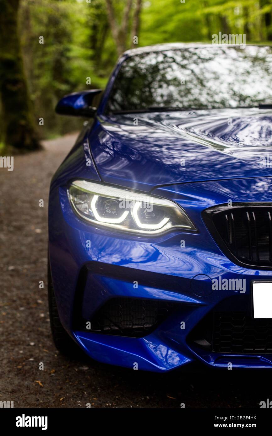 Blue sedan driving in the romantic forest under green trees, front ...