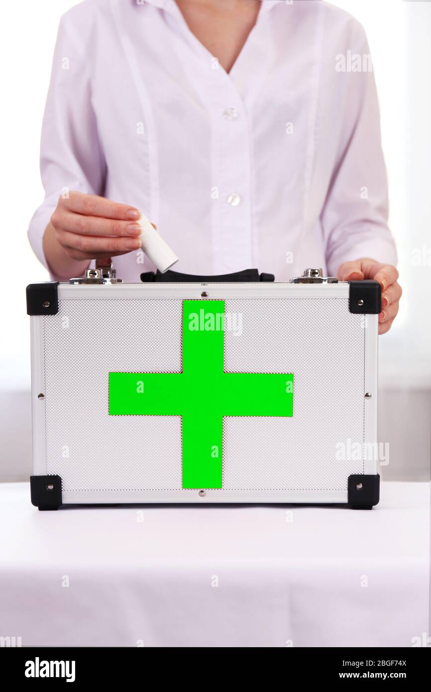 Nurse holding first aid kit in room Stock Photo - Alamy